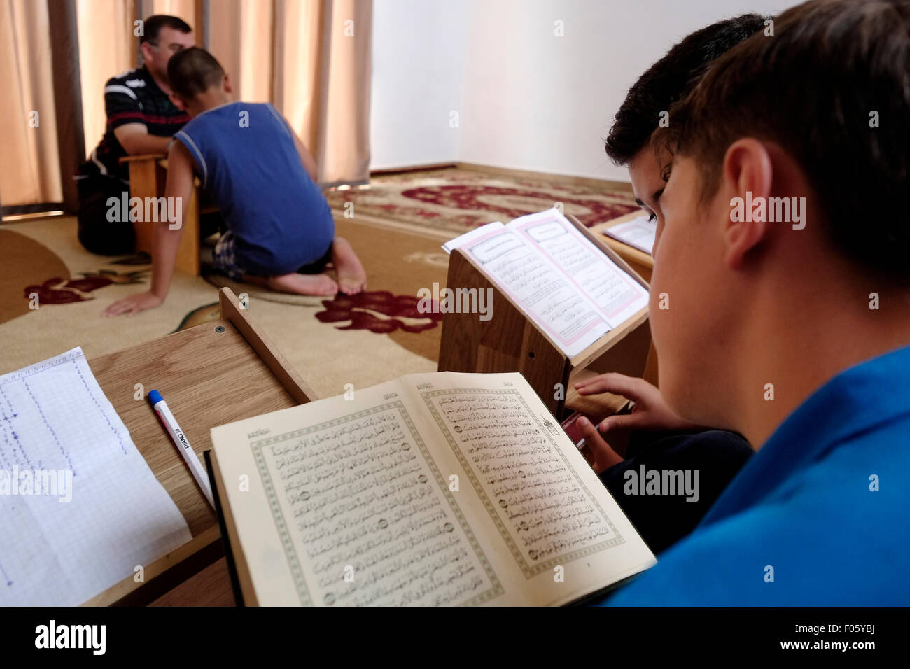 A young Muslim boy reading the Koran holy book during Islamic lecture ...