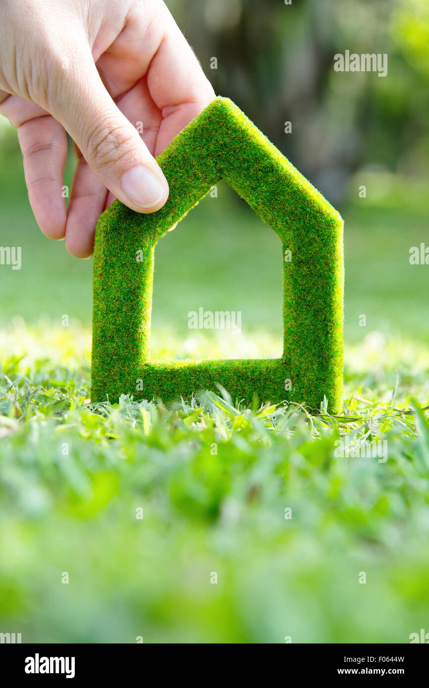 Hand holding green house icon with nature background Stock Photo - Alamy