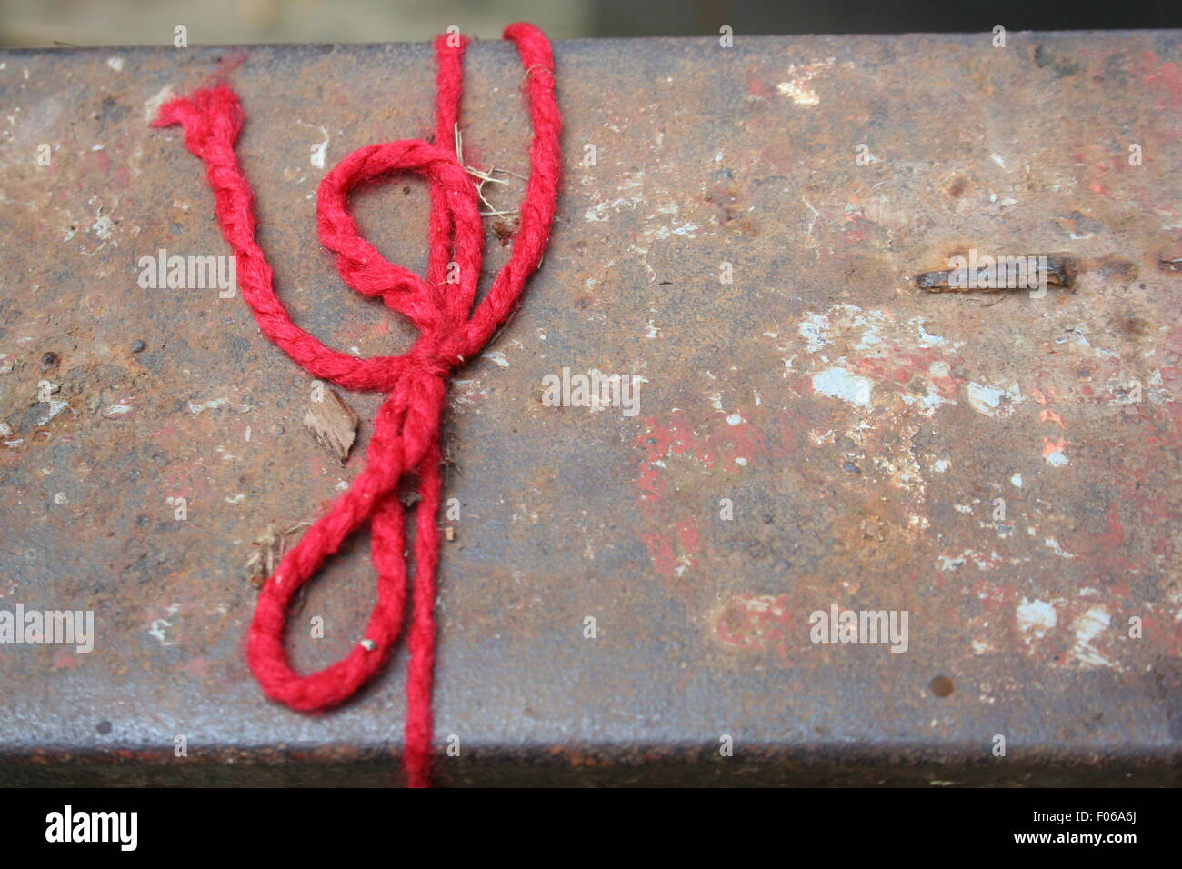 Tied red string on a weathered bench Stock Photo - Alamy