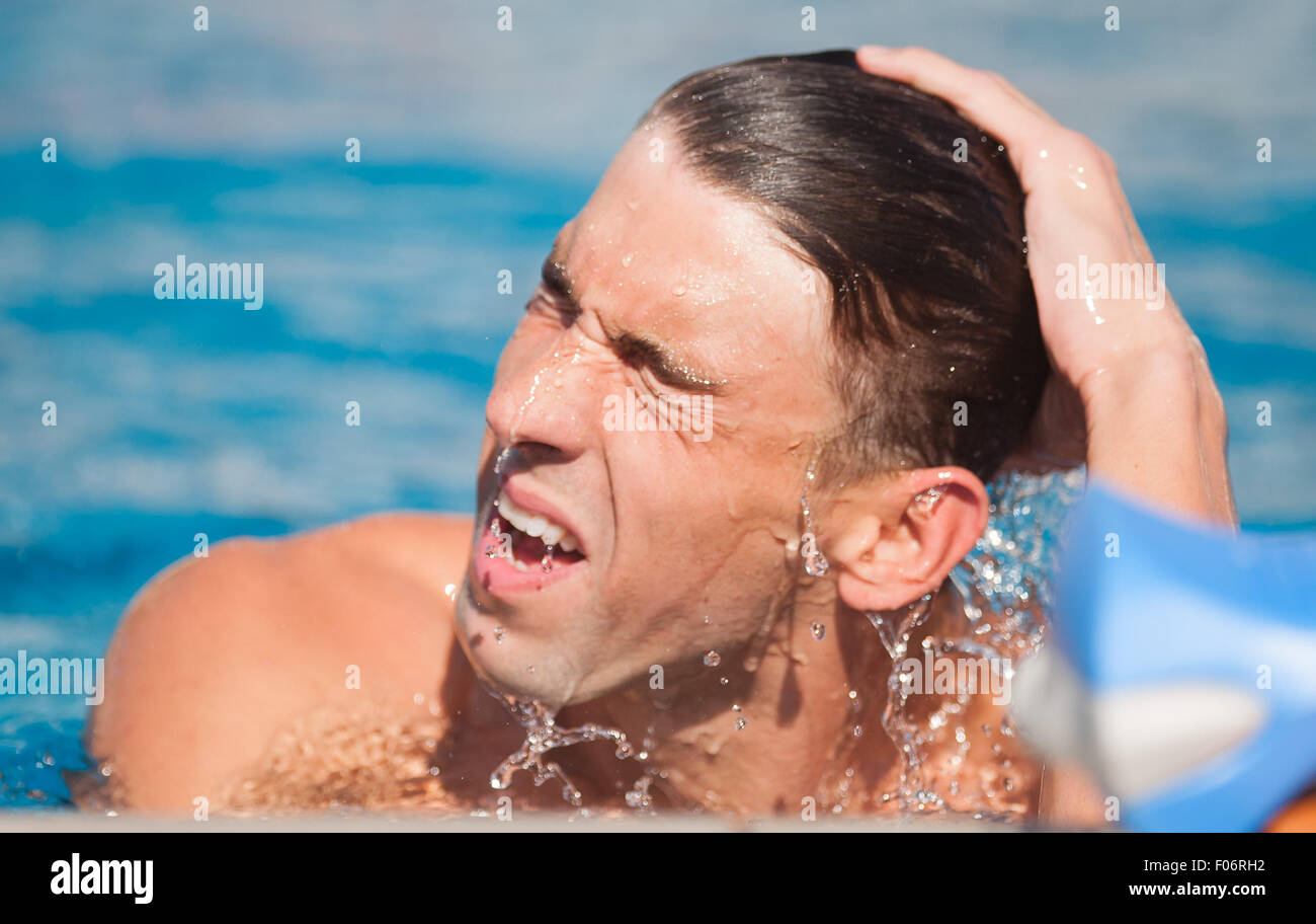 Michael Phelps wipes the water from his face while warming up during ...