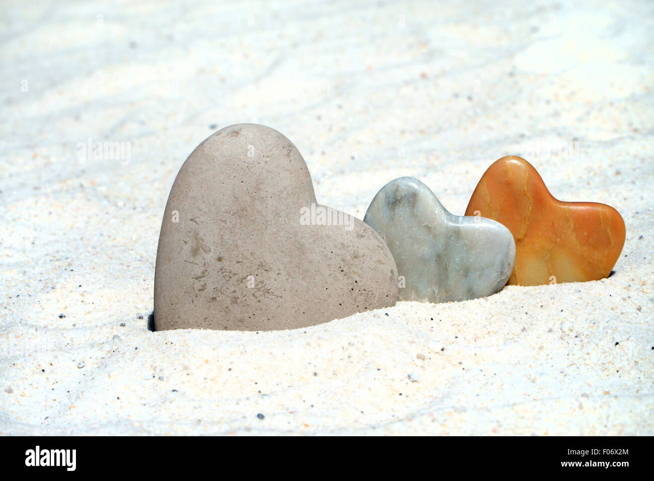 Large and two small stone hearts in the sand Stock Photo - Alamy