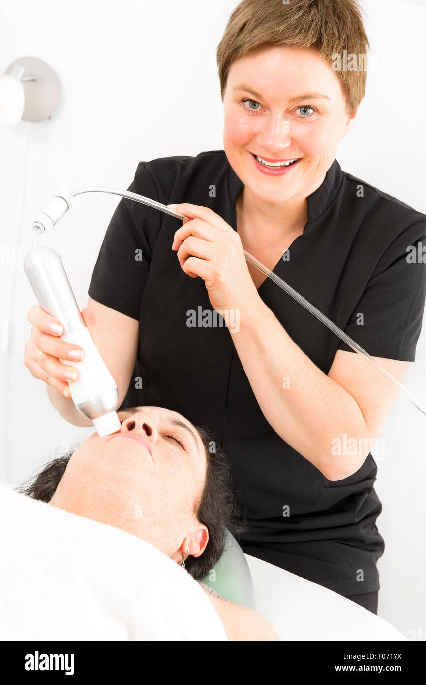 Client get face treatments by smiling therapist Stock Photo - Alamy