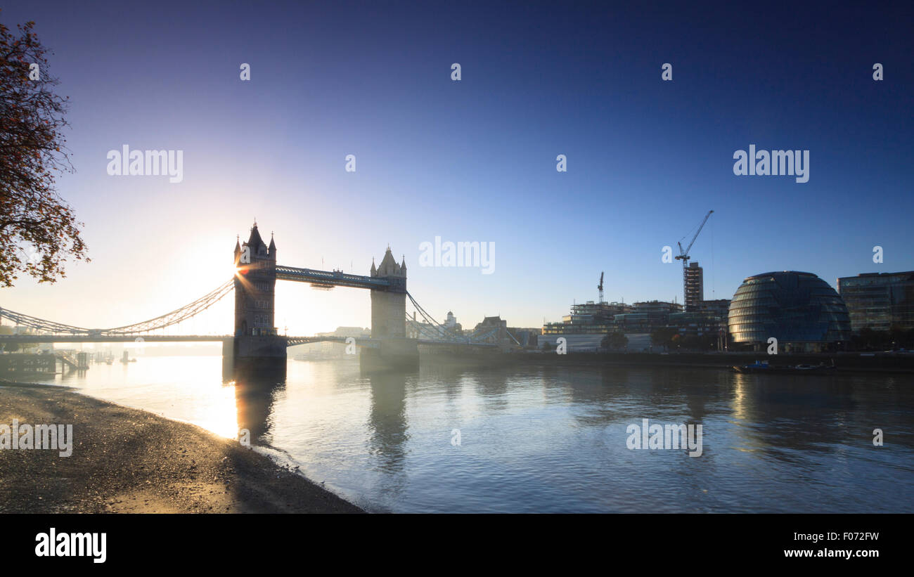 The sun rises behind Tower Bridge, London, on a clear, cold, November ...