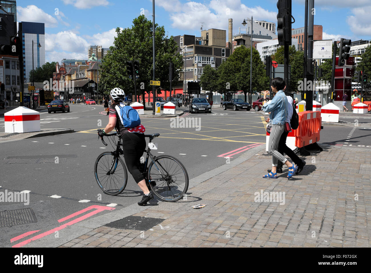 A woman pushes off from the curb on a bicycle in Old Street East London ...