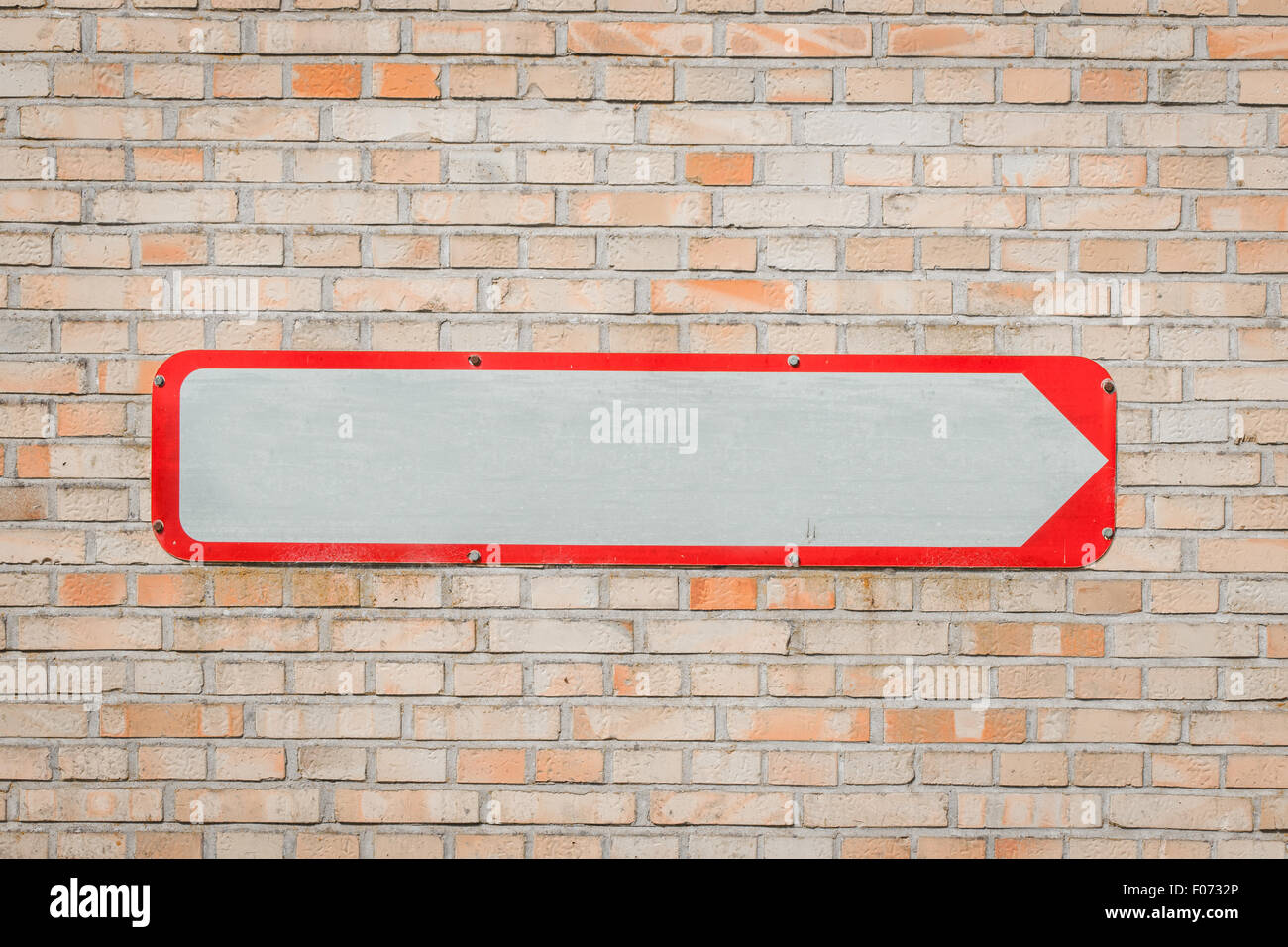 Metal sign with an arrow on a brick wall Stock Photo - Alamy