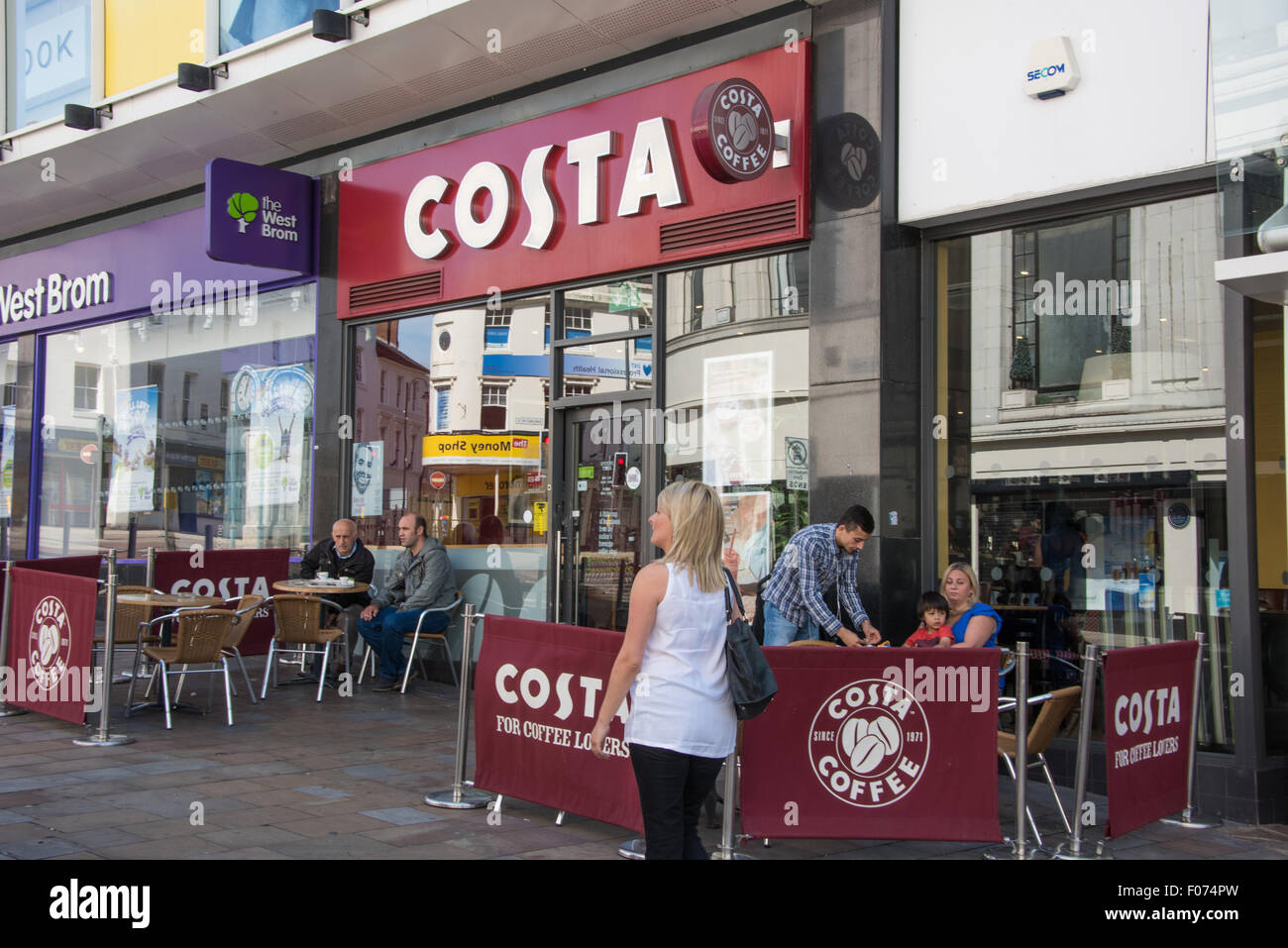 People sitting outside Costa as a woman walks past on high street ...