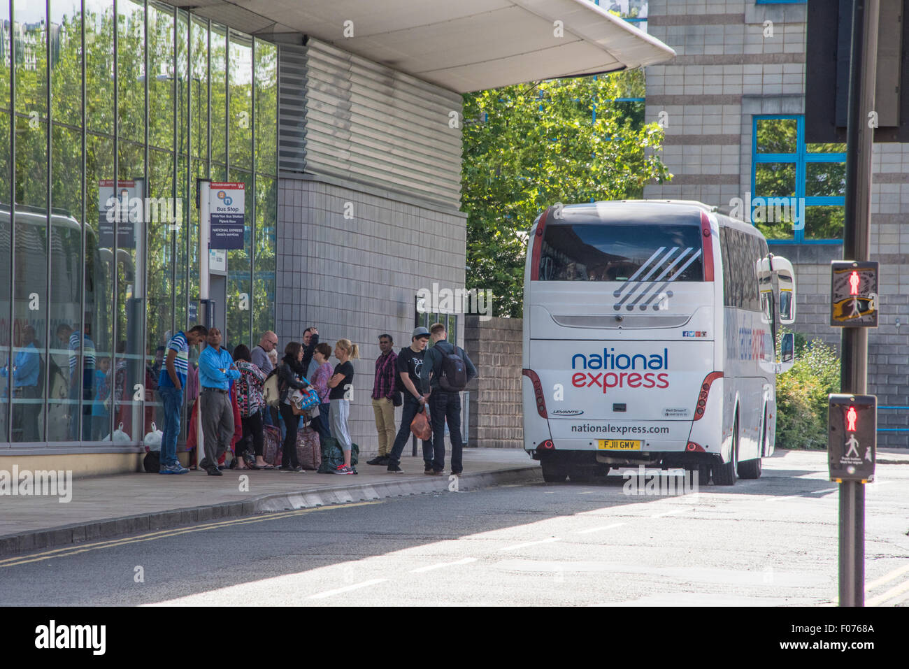 A group of people waiting to board a National Express coach at ...
