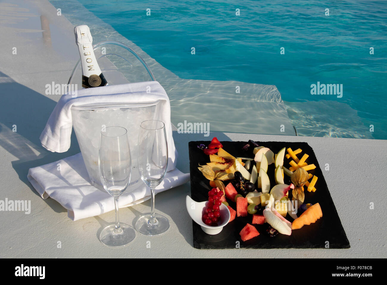 Champagne Moet white bottle and fresh fruits dish by the pool Stock ...