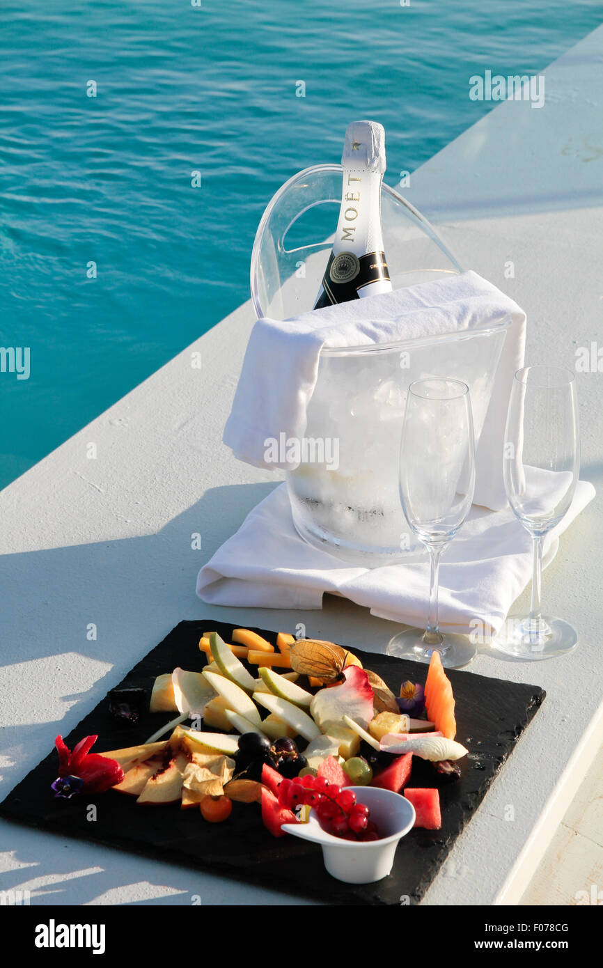Champagne Moet white bottle and fresh fruits dish by the pool Stock ...