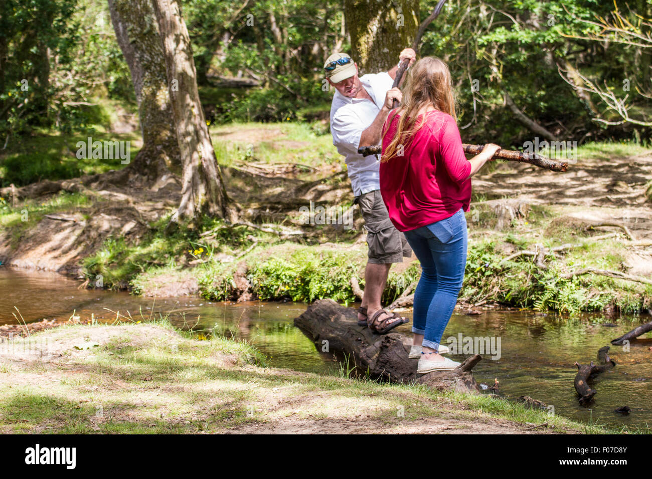father and daughter competing playing sticks on log over stream Stock ...