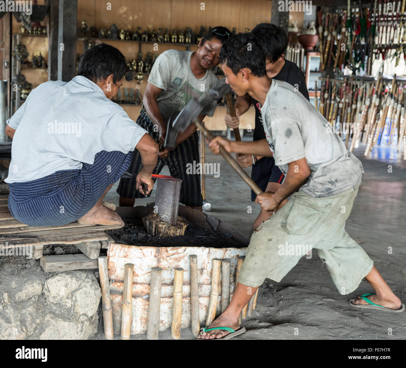 Blacksmiths shape red-hot steel blade at anvil in Sei Kaune village on ...