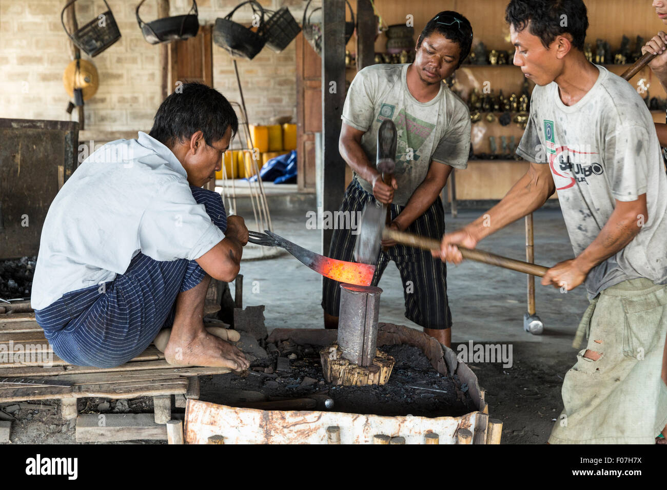 Blacksmiths shape red-hot steel blade at anvil in Sei Kaune village on ...