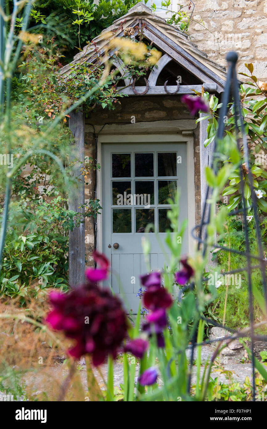 The door of a quintessential english country cottage with wild flowers ...