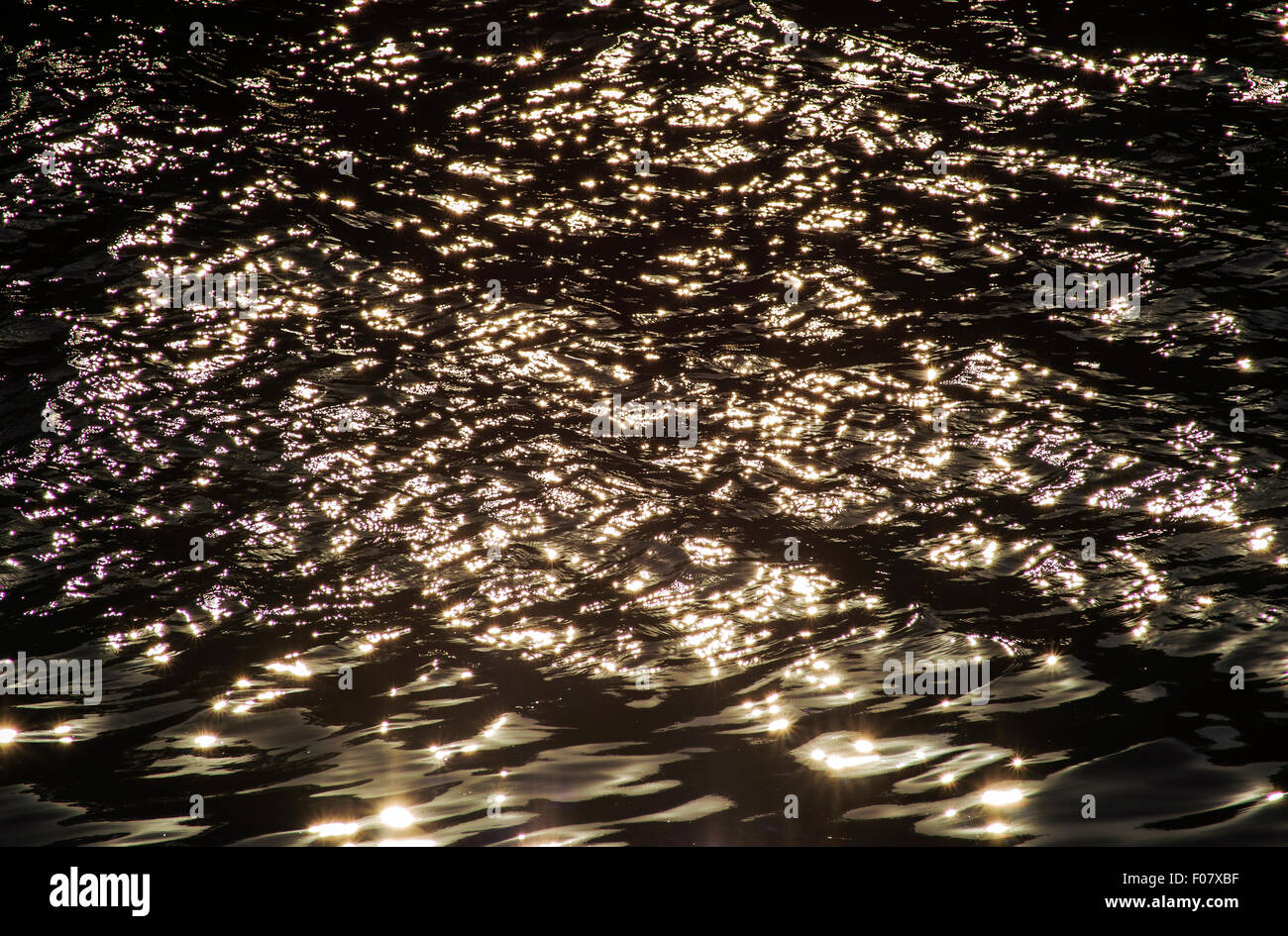 Light from the sun on a black water for background Stock Photo - Alamy