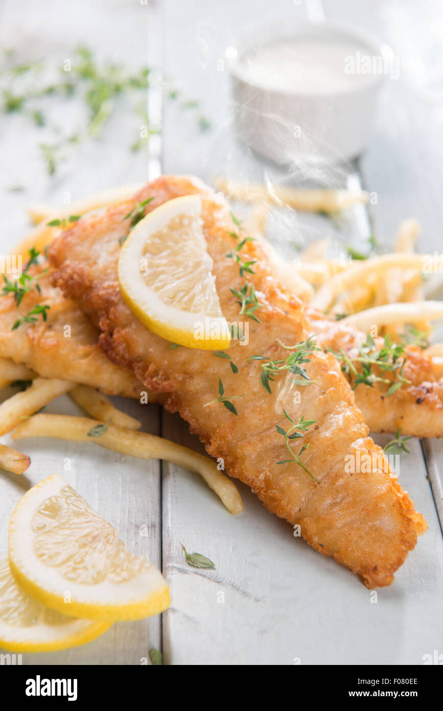 Fish and chips. Fried fish fillet with french fries on bright wooden ...