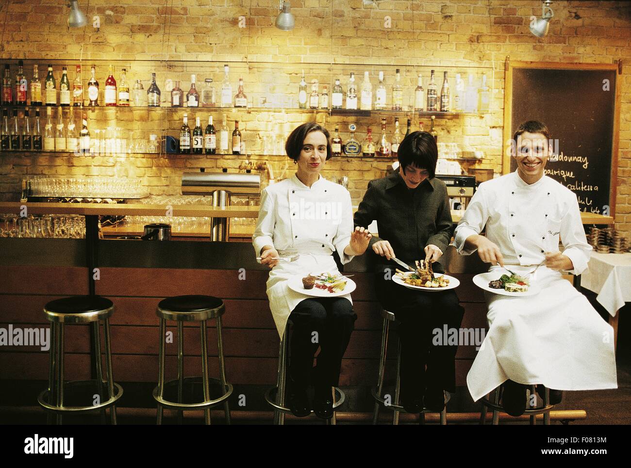Three chef sitting in front of bar counter and eating food, Restaurant ...