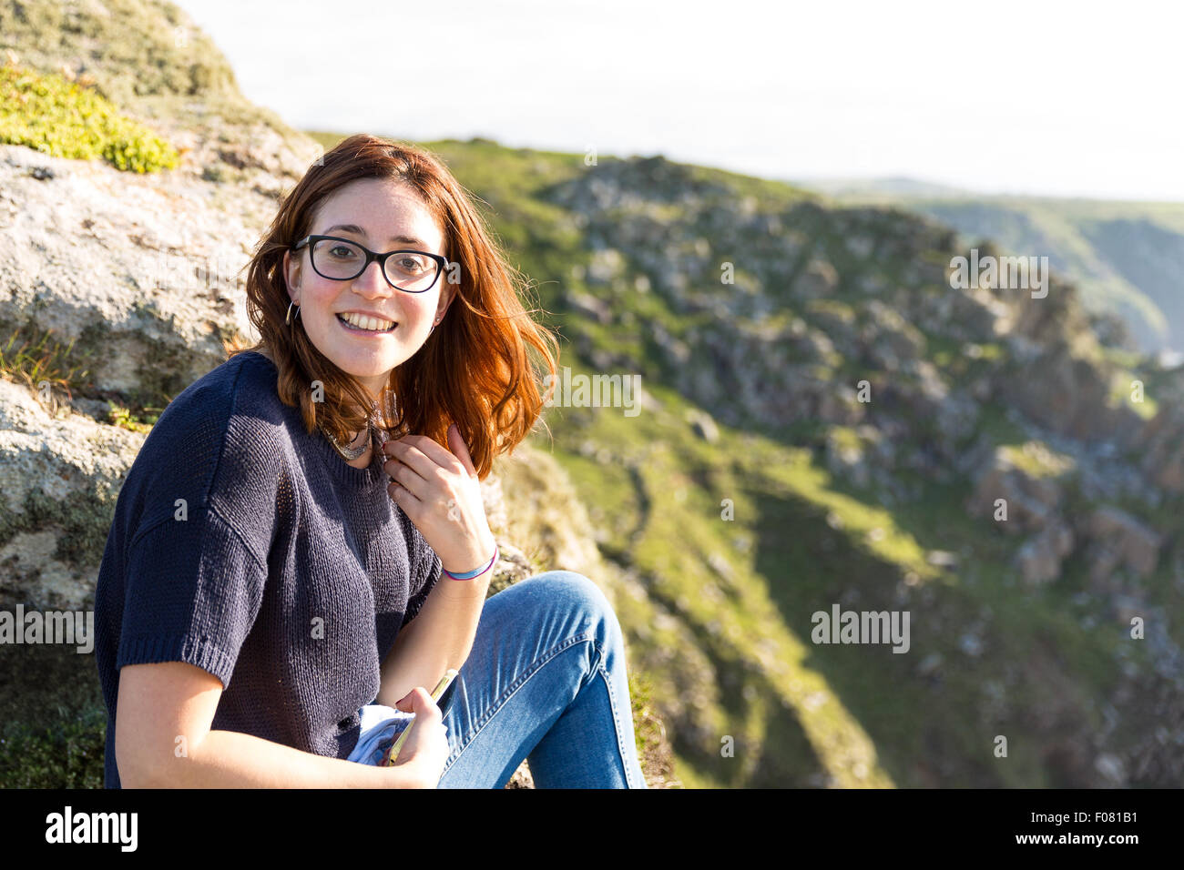 Young woman with red hair at Portmehor Point, Carn Galver, Cornwall, UK ...