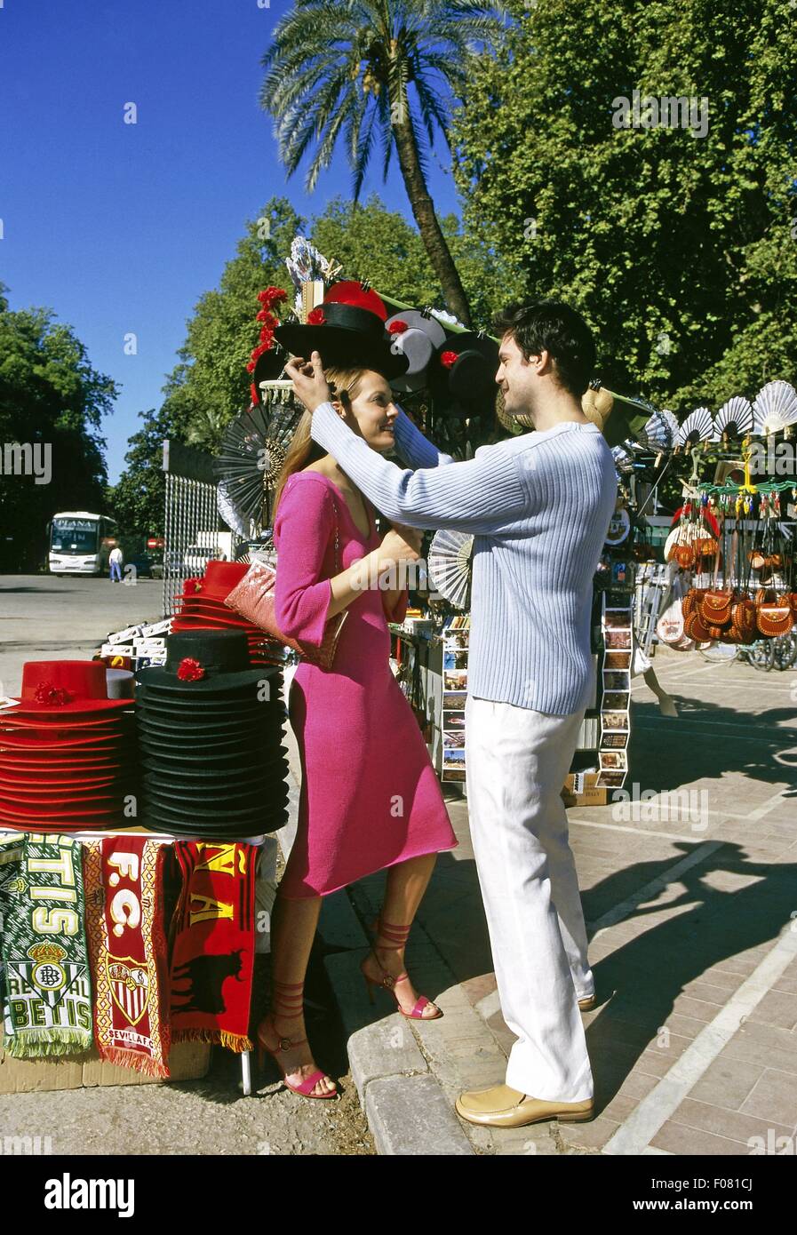 Man putting hat on woman at flea market Stock Photo - Alamy