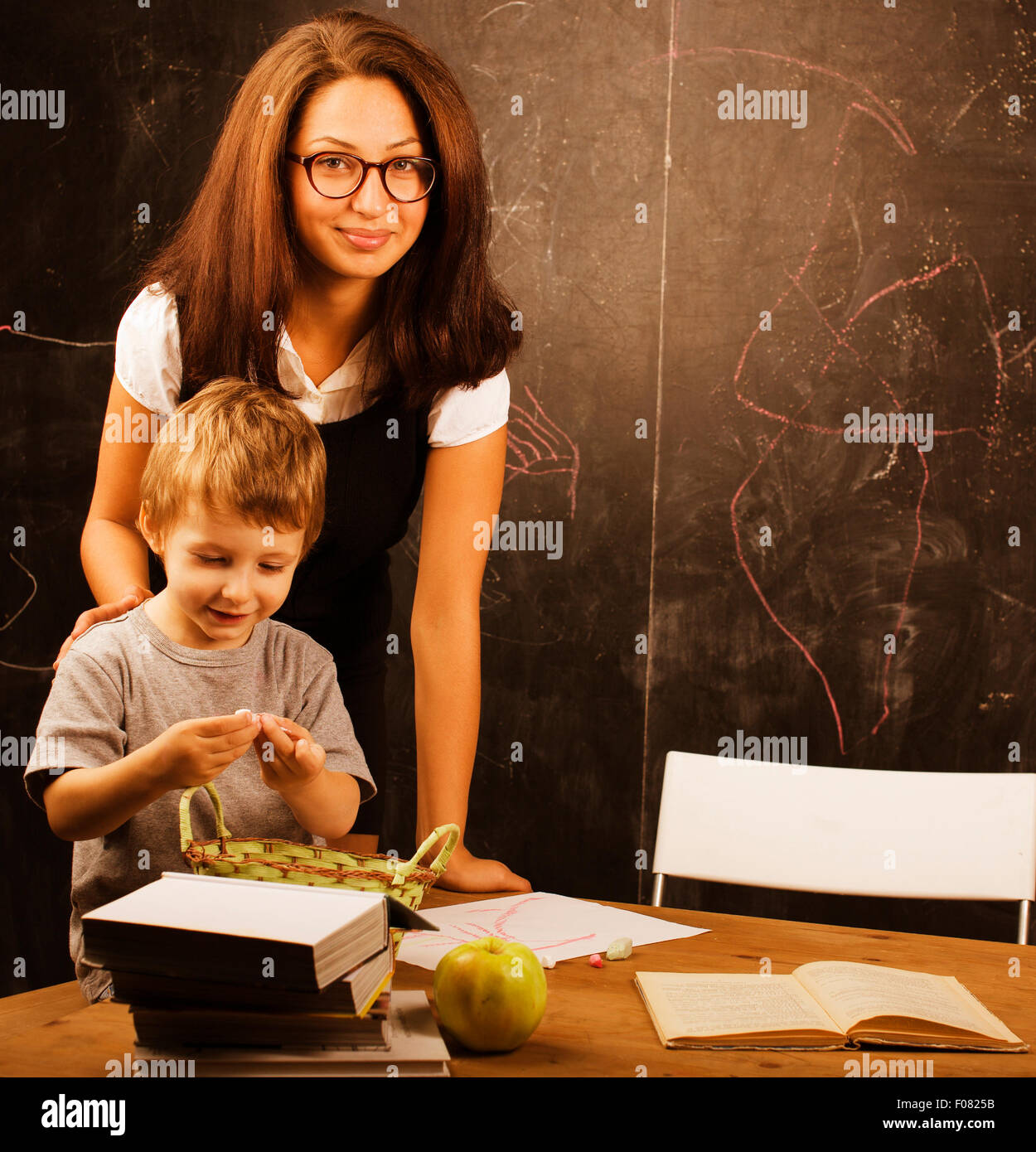 little cute boy in glasses with young real teacher, classroom studying ...