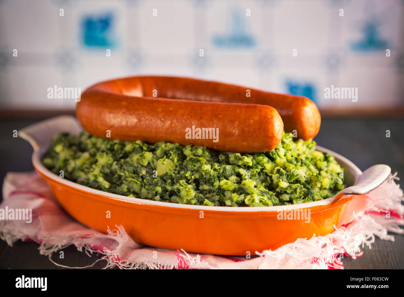 A rustic kitchen with a dish with 'Boerenkool met worst' or kale with ...