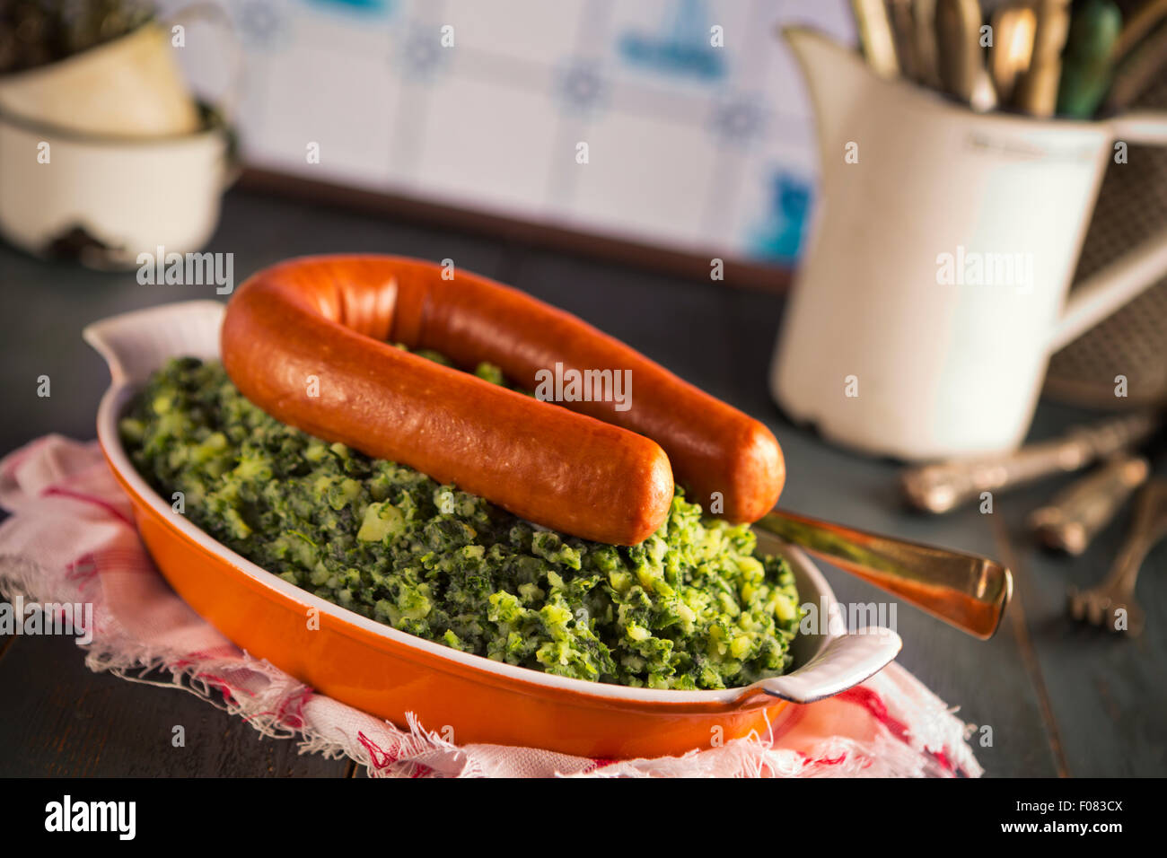 A rustic kitchen with a dish with 'Boerenkool met worst' or kale with ...