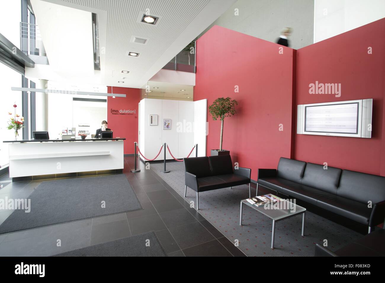 Receptionist standing at reception counter with sitting area in hotel ...
