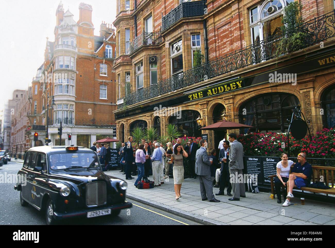 People waiting and passing on the street at Audley Pub in London, USA ...