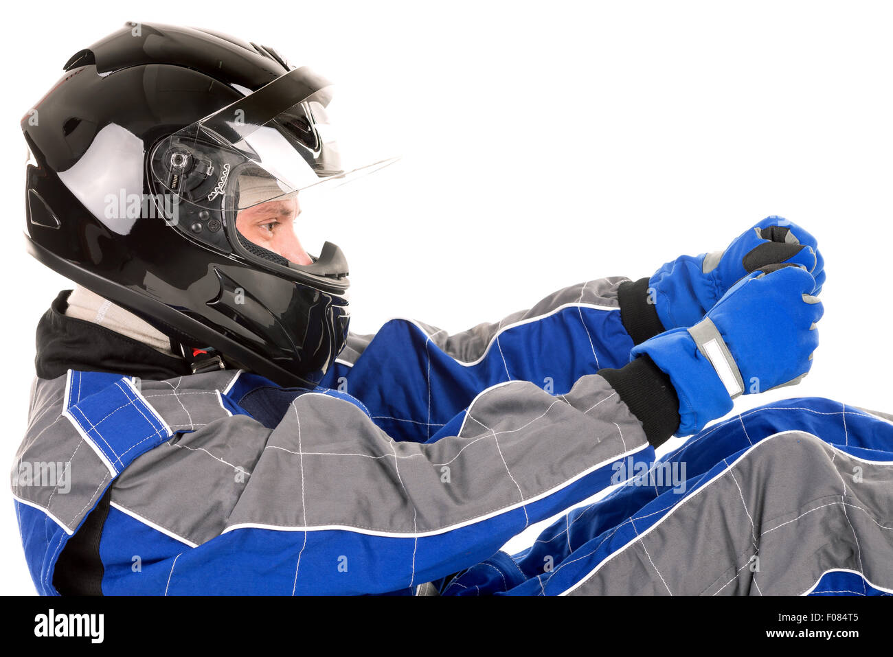 Racing driver posing in driving position in full gear isolated in white ...