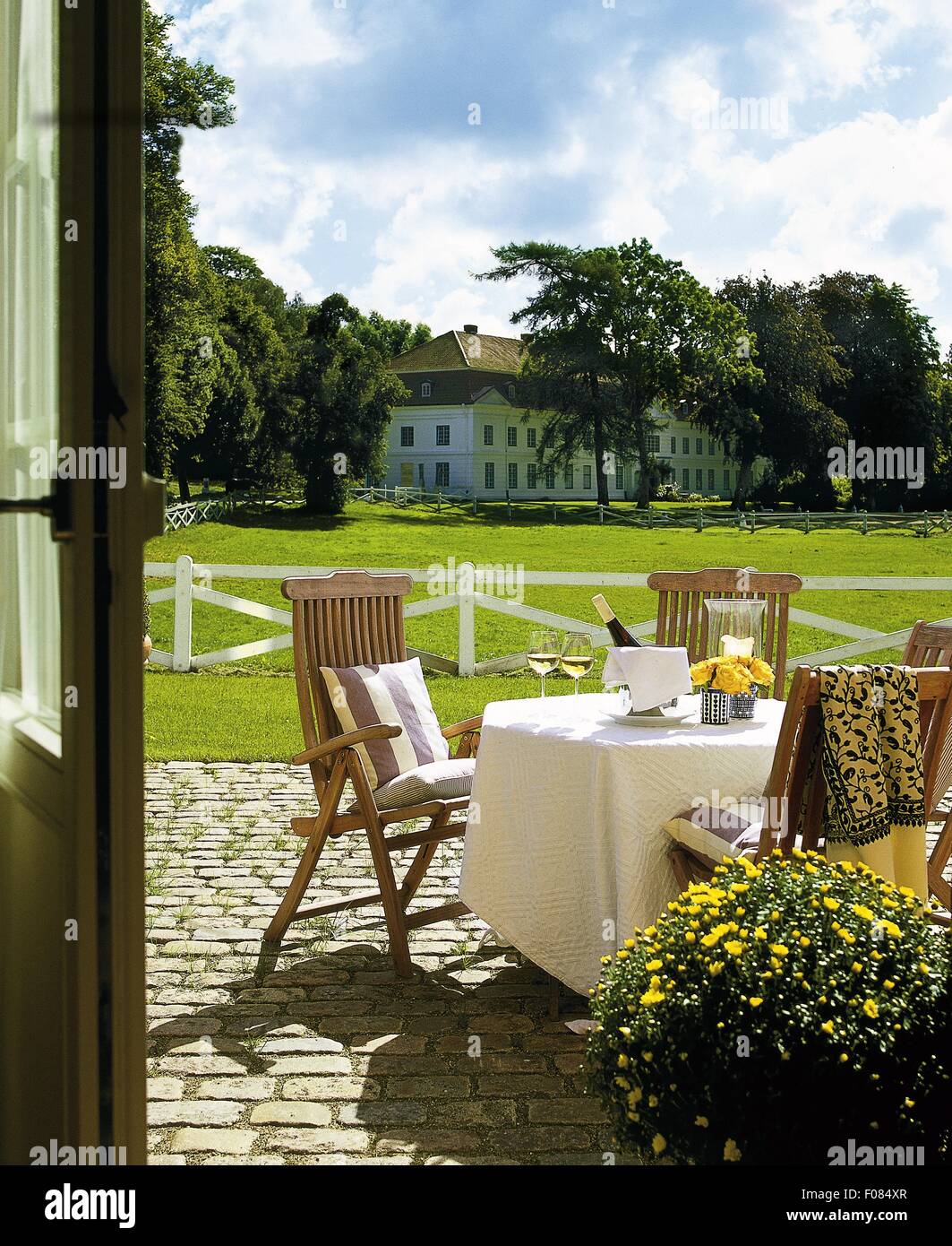 Terrace with table, chairs and large lawn in front Stock Photo - Alamy