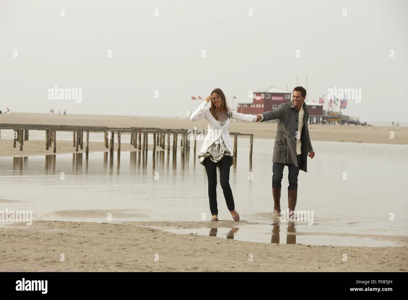 Couple fooling around while walking hand in hand on beach Stock Photo ...
