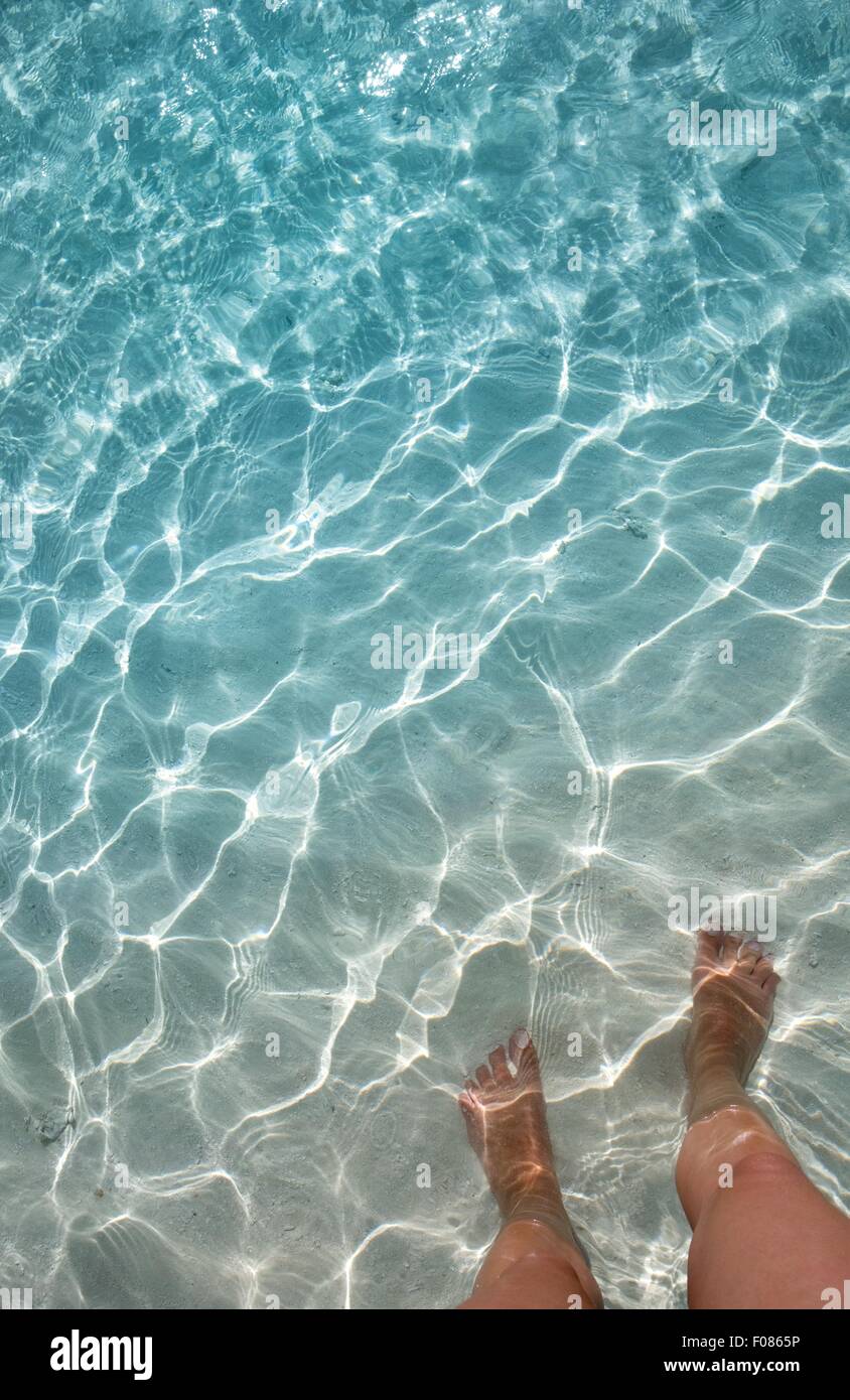 Close-up of feet in shallow water, Veliganduhuraa island, Maldives ...