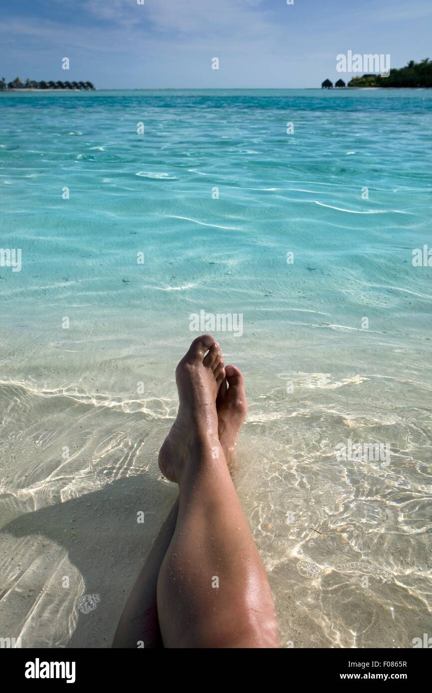 Close-up of legs in shallow water in Veliganduhuraa island, Maldives ...