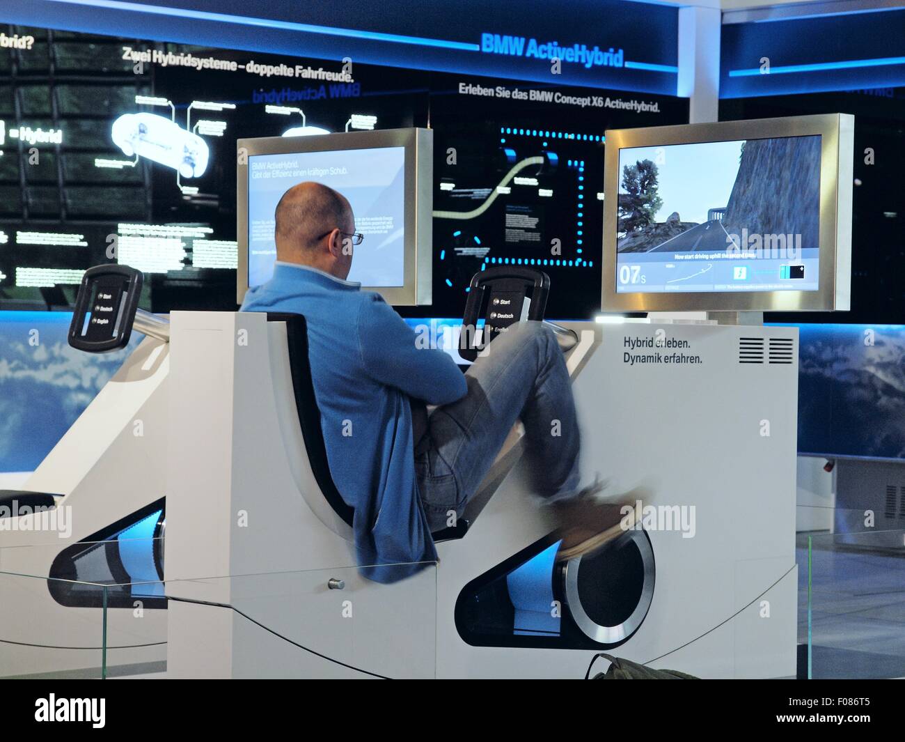 Rear view of man sitting on driving simulator in BMW World, Munich ...