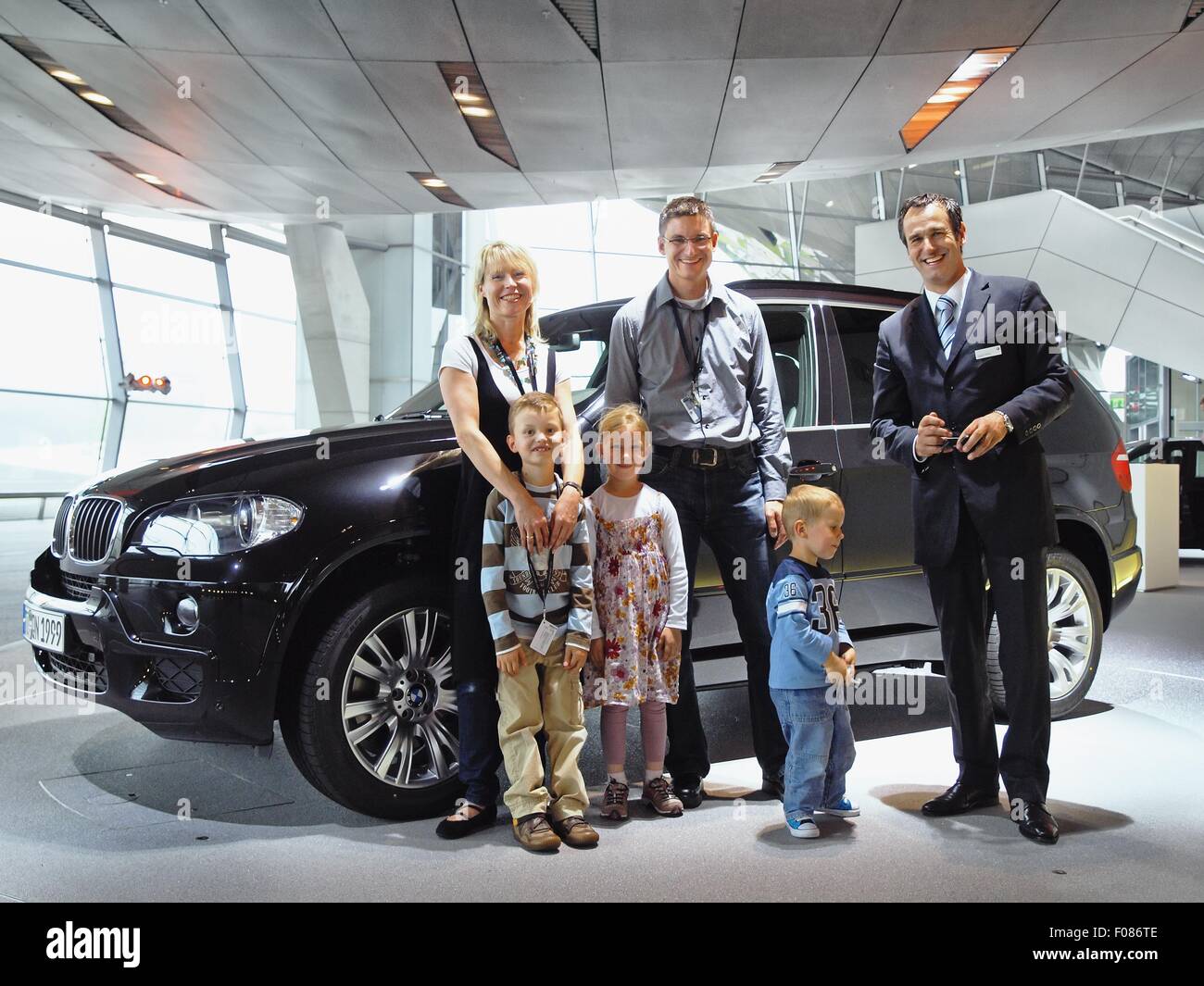 Happy family with staff in front of car, BMW World, Munich, Germany ...