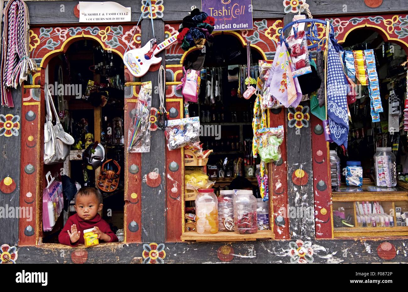 Child looking through window of shop, Bhutan Stock Photo - Alamy