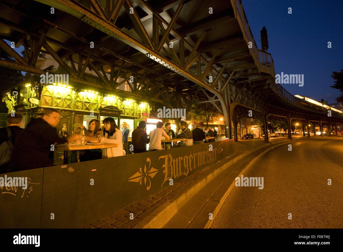 People dinning at restaurant under bridge in evening lights, Berlin ...