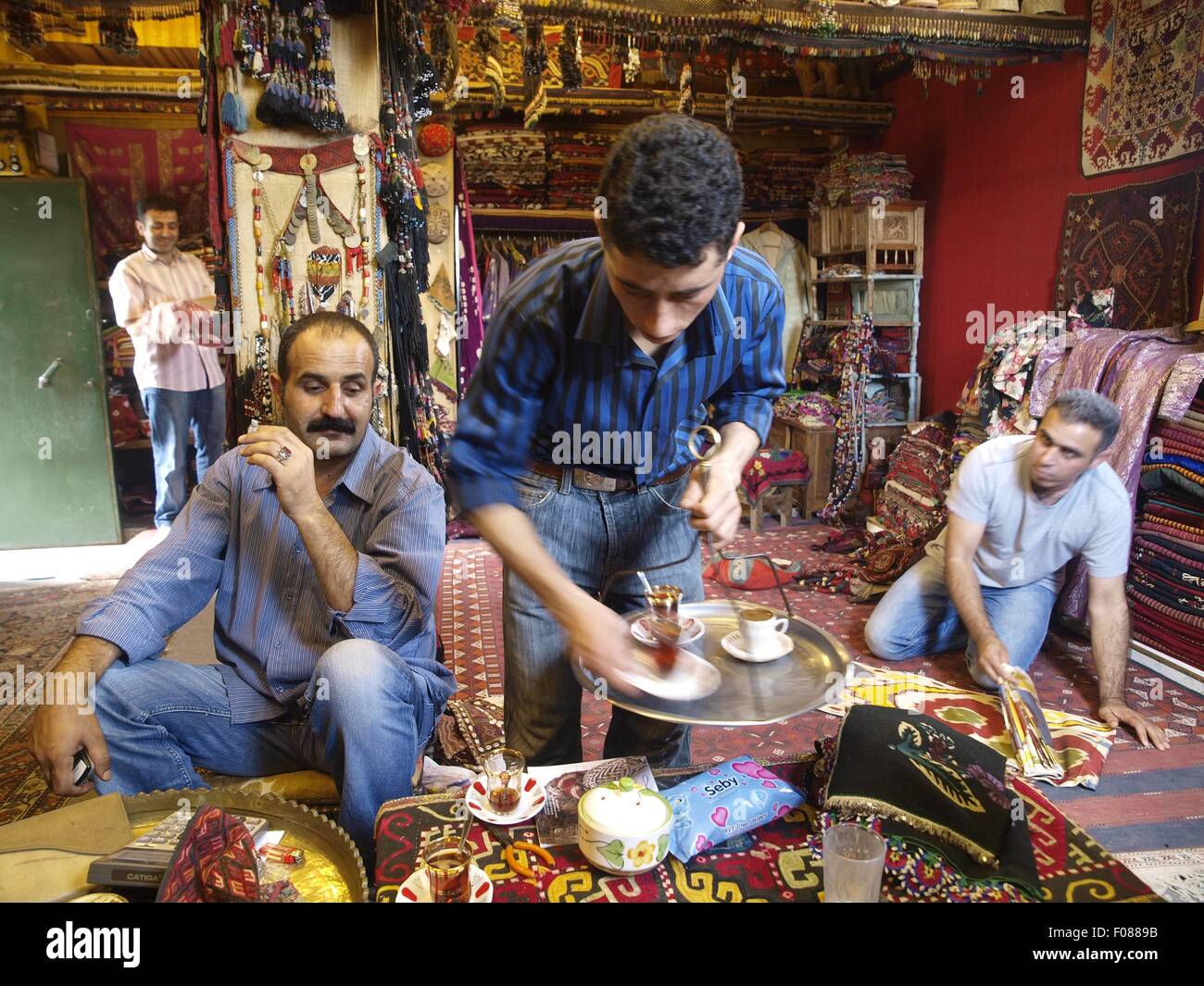 Man serving tea to business men at Grand Bazaar fabric store in ...