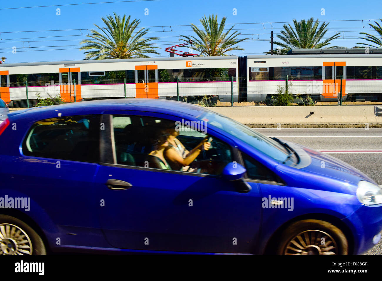 Blue car on road and Rodalies, Cercanias Renfe train. Maresme ...