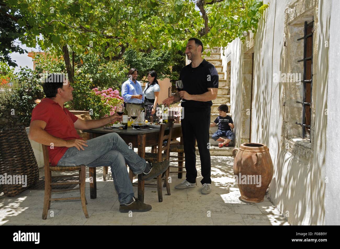 Two men drinking wine under tree in Crete, Greece Stock Photo - Alamy