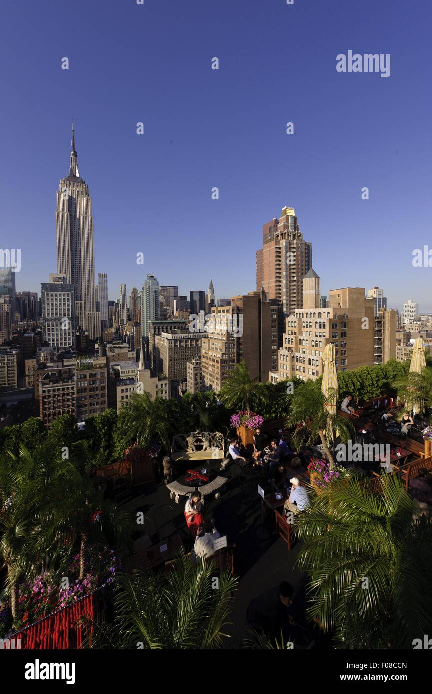 View of cityscape overlooking people sitting on rooftop bar at New York ...