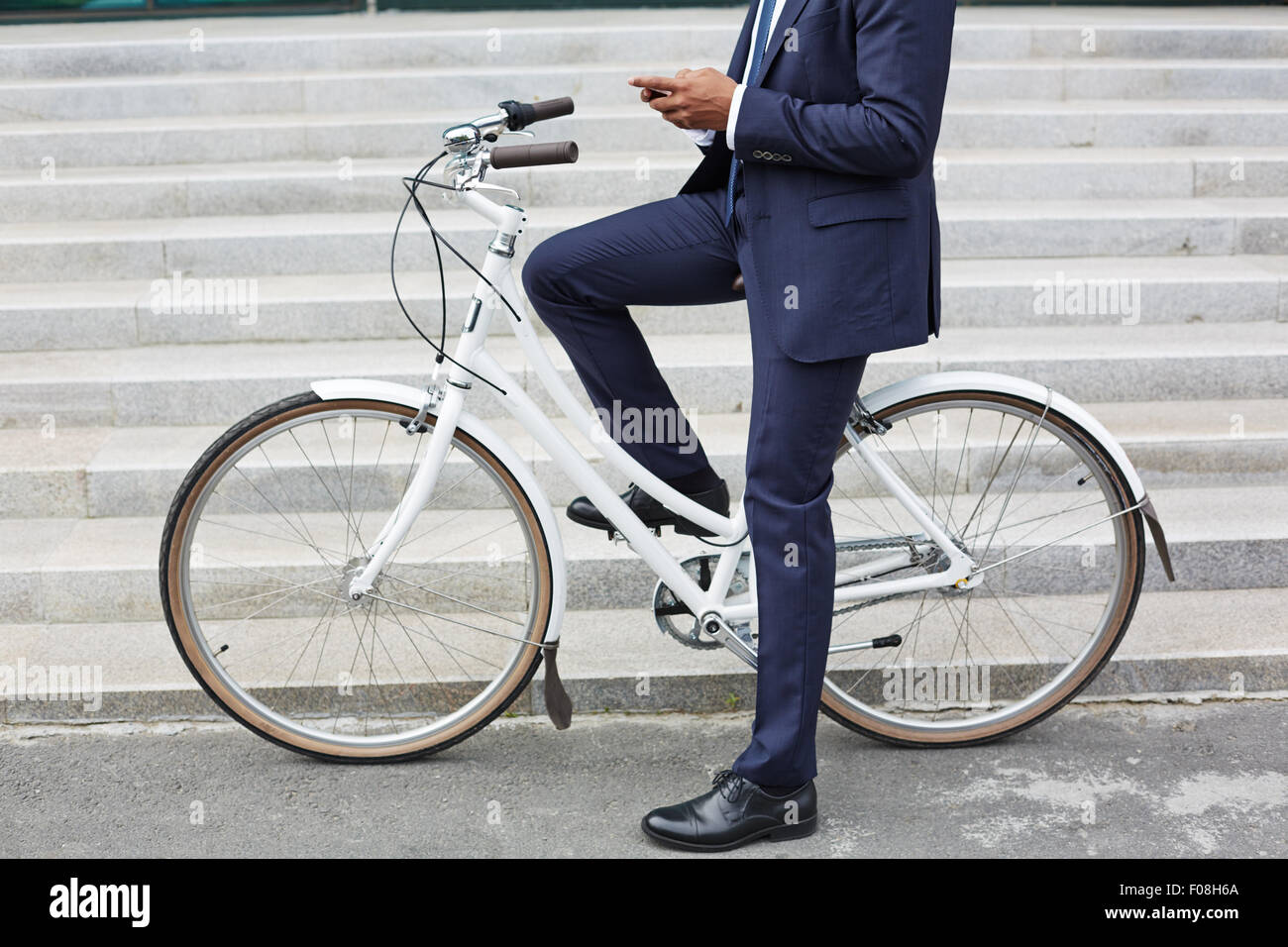 Modern businessman on bicycle writing sms in urban environment Stock ...