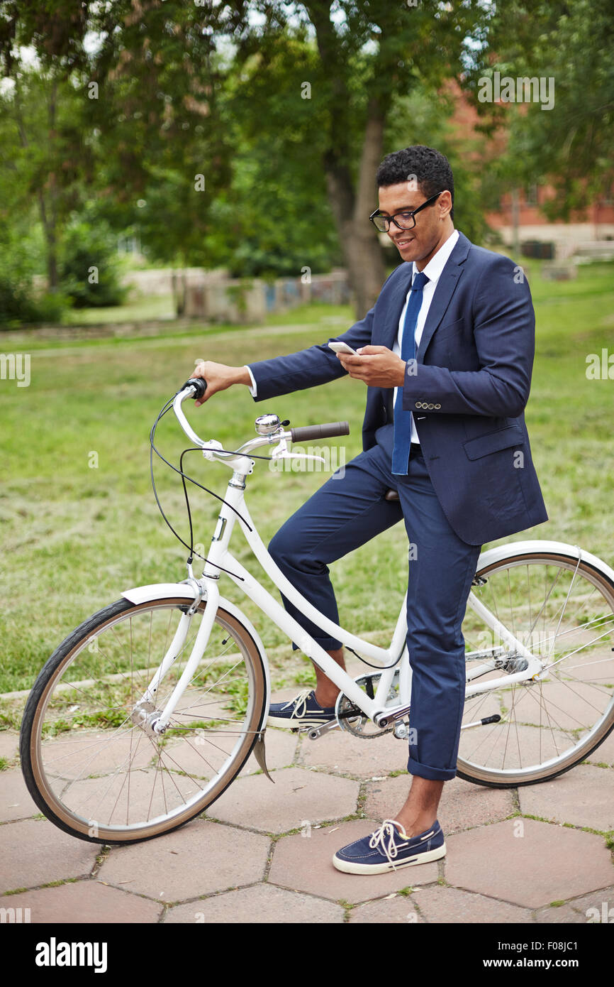 Modern and active employee with cellphone and bicycle reading sms in ...