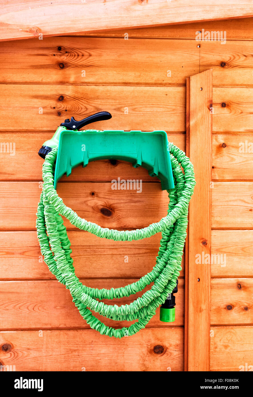Flexible non-kinking green garden hose hanging on the side of a shed ...