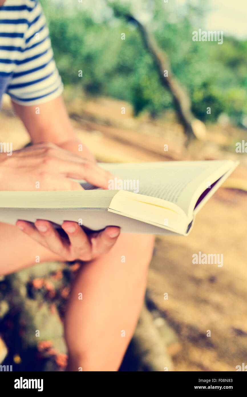 closeup of a young caucasian man reading a book outdoors in a natural ...