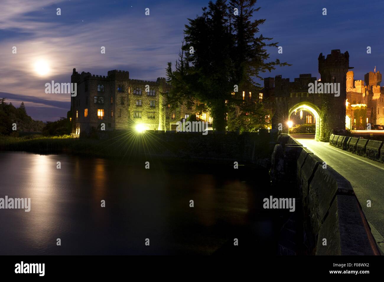 Illuminated Ashford Castle and Bridge over Cong canal at dusk, Ireland ...