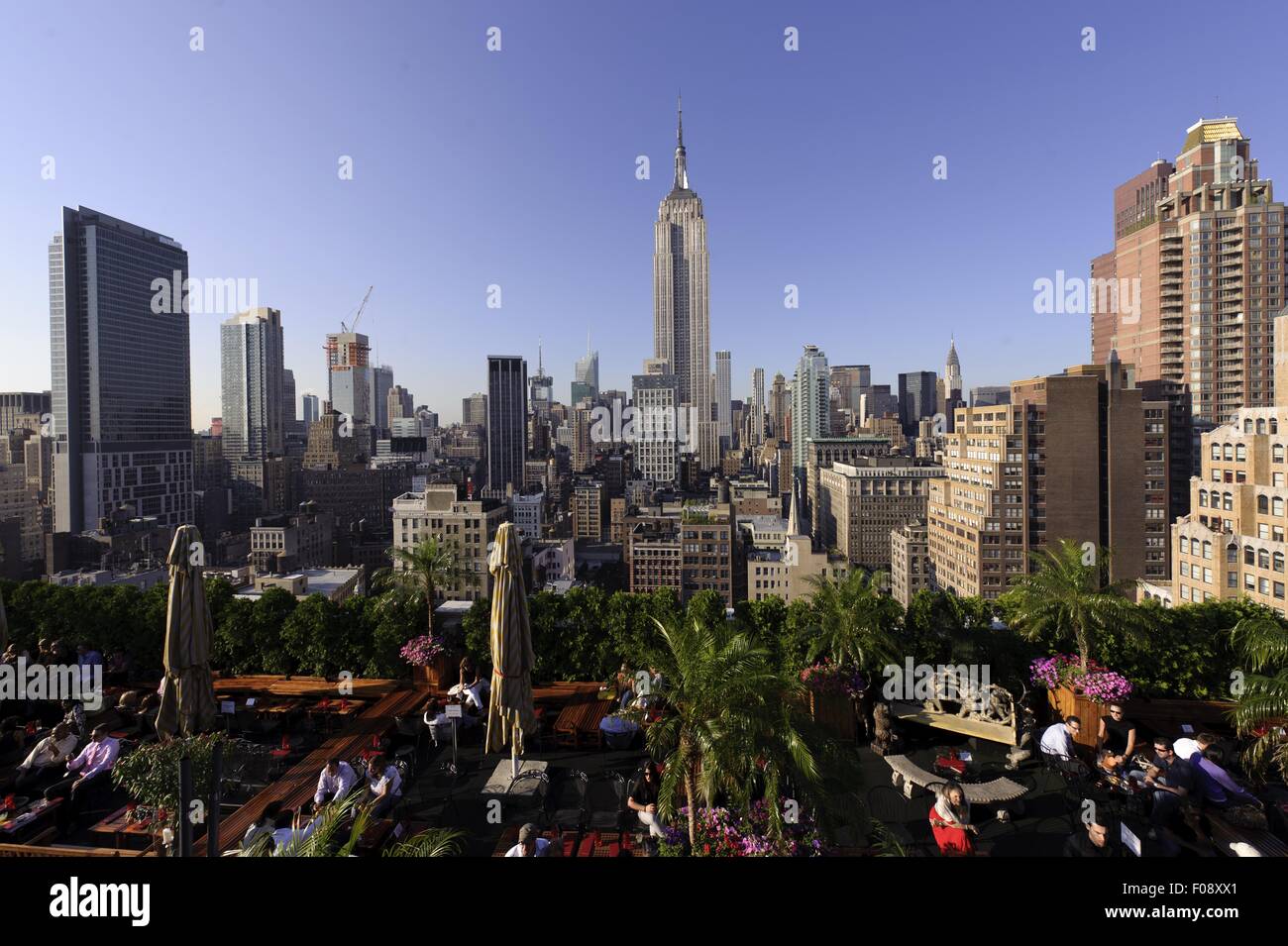 View of cityscape overlooking people sitting on rooftop bar at New York ...