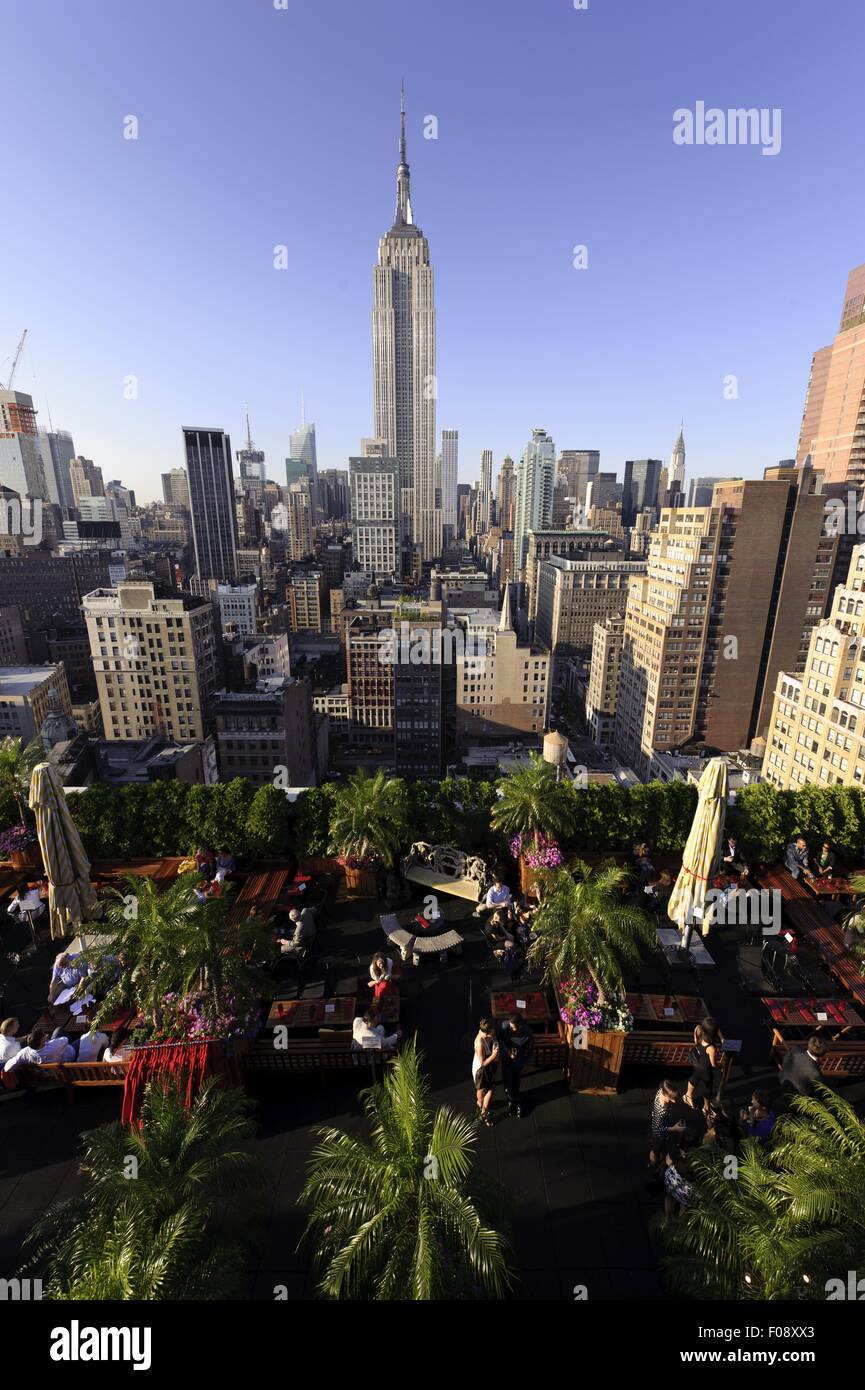 View of cityscape overlooking people sitting on rooftop bar at New York ...