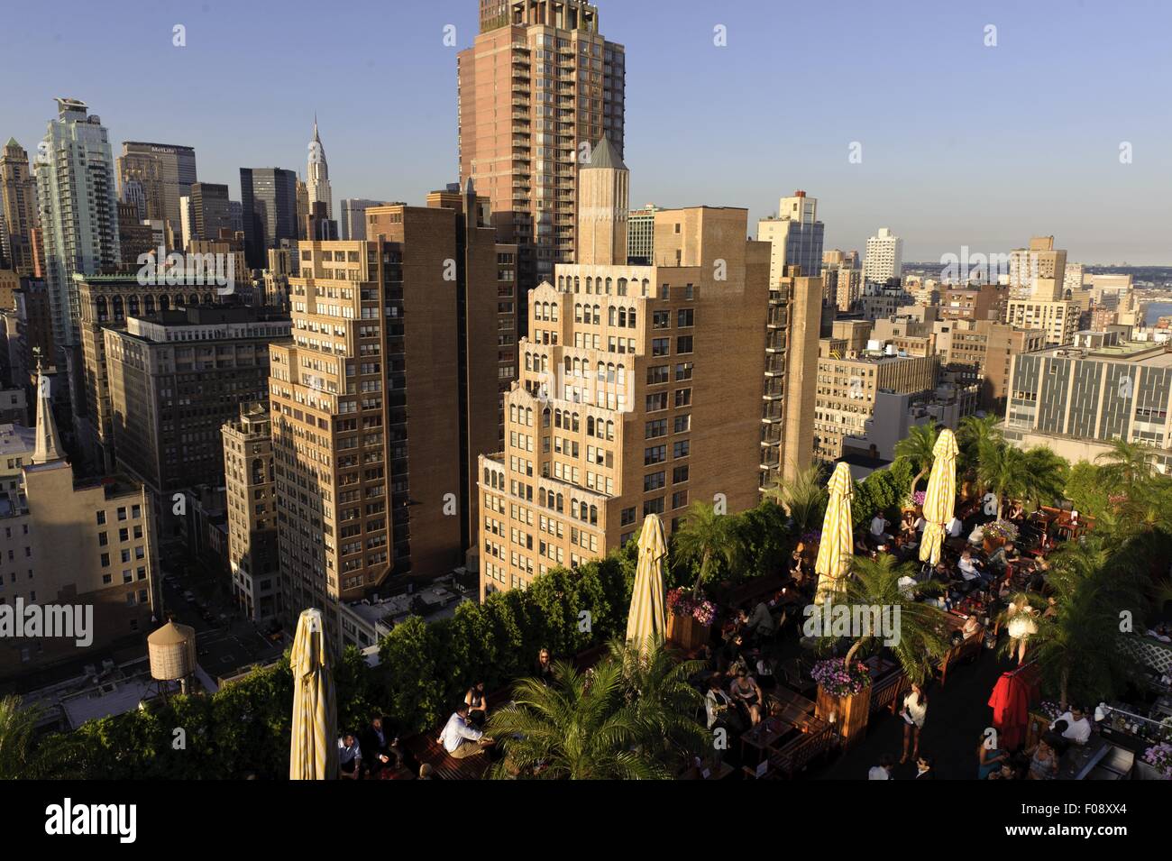 View of cityscape overlooking people sitting on rooftop bar at New York ...
