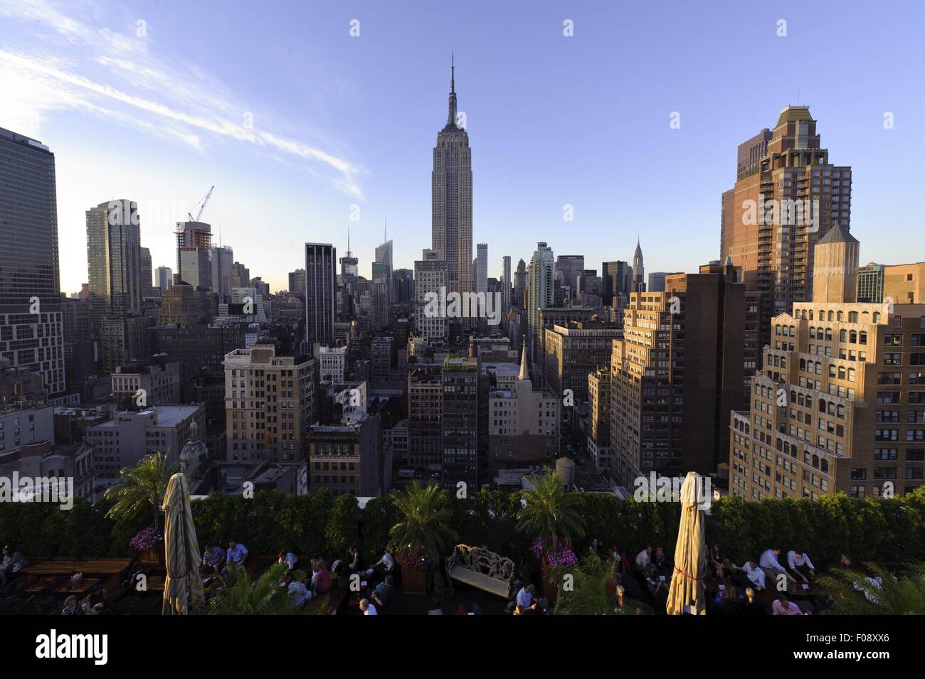 View of cityscape overlooking people sitting on rooftop bar at New York ...