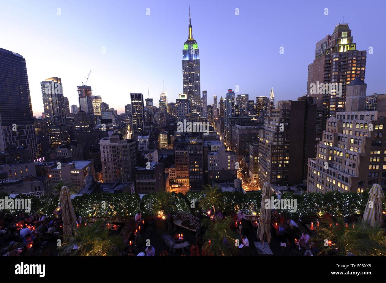 View of cityscape overlooking people sitting on rooftop bar at New York ...